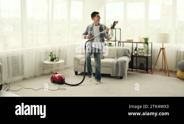 Young and active Caucasian individual is seen dancing while cleaning in ...