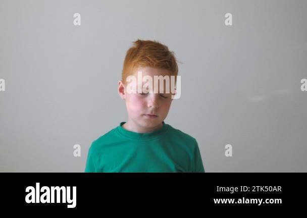 Young kid looking at camera and touch his face expressing a desperate ...