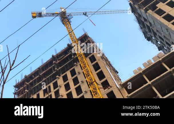 Bottom view of a yellow high-rise construction crane. Construction of a ...