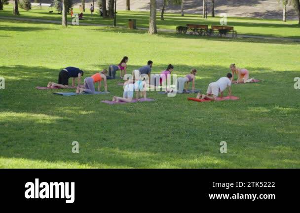 Female coach teaching practitioners perform stretching exercises ...