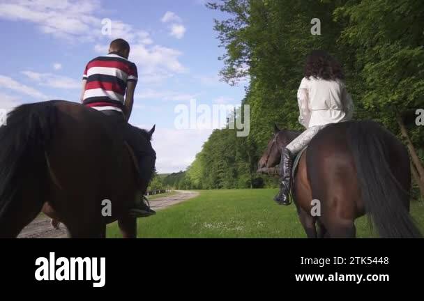 Rear view of happy family couple riding horses together in the green ...