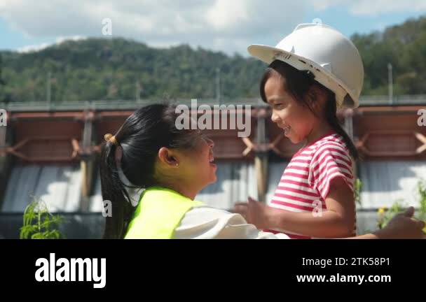 Engineer mother, wearing helmet to her daughter against background of ...