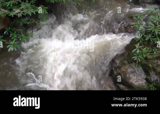 Clear natural mountain stream running down splashing over boulder in ...