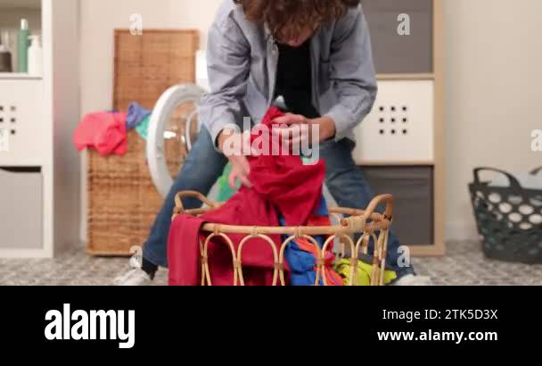 Happy causasian teen boy throwing dirty clothes into washing machine as ...
