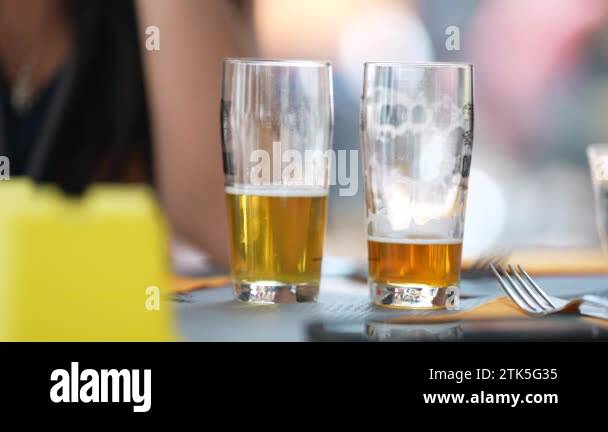 Half empty glasses of beer at restaurant table. Two drank draft beers half full Stock Video ...