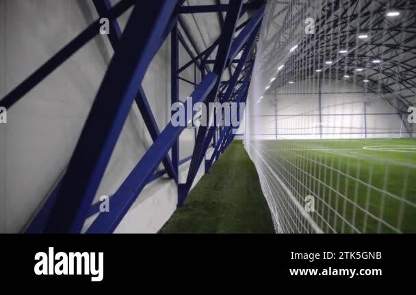 Mesh hanging around large indoor football court with green turf and ...