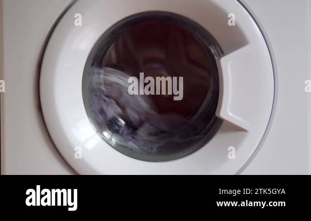 Washing clothes in a household washing machine at home. spinning drum ...