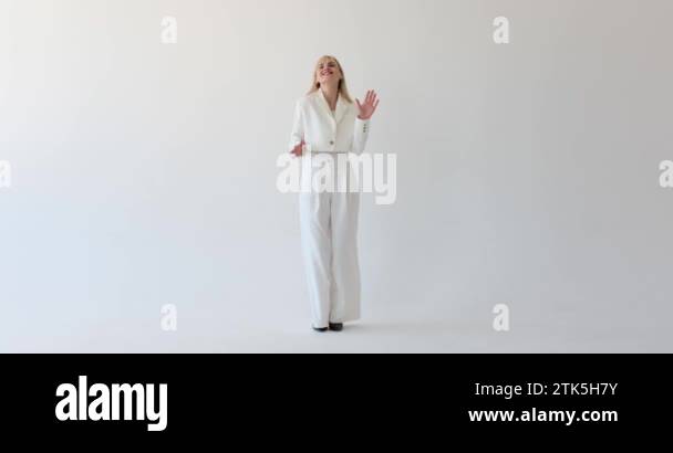 Energetic woman is seen on a clean white backdrop, dancing with ...