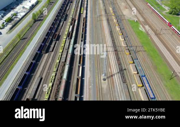 Flying above industrial railroad station with cargo trains and freight ...