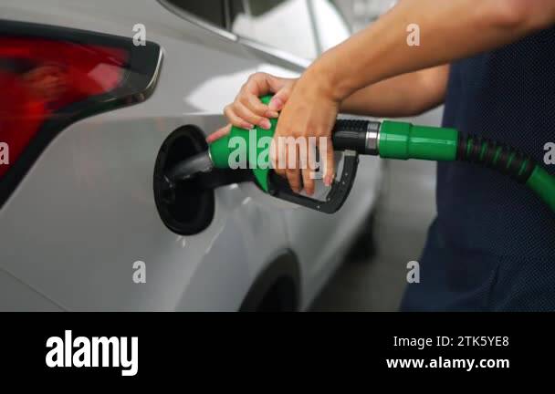 Woman inserts a fuel gun in a gas tank to refuel a car. Concept of ...