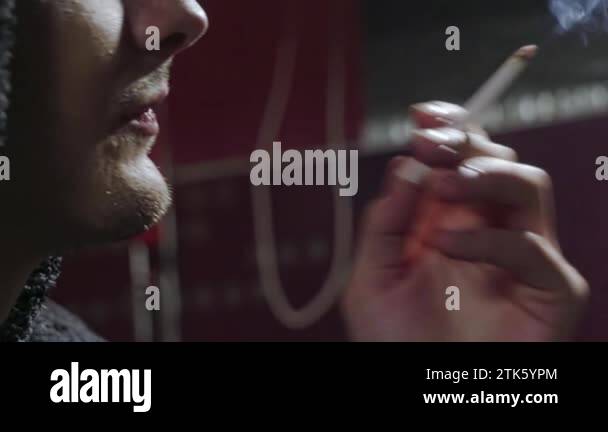 Guy, licking his lips, lights cigarette, exhaling smoke up, close-up in ...