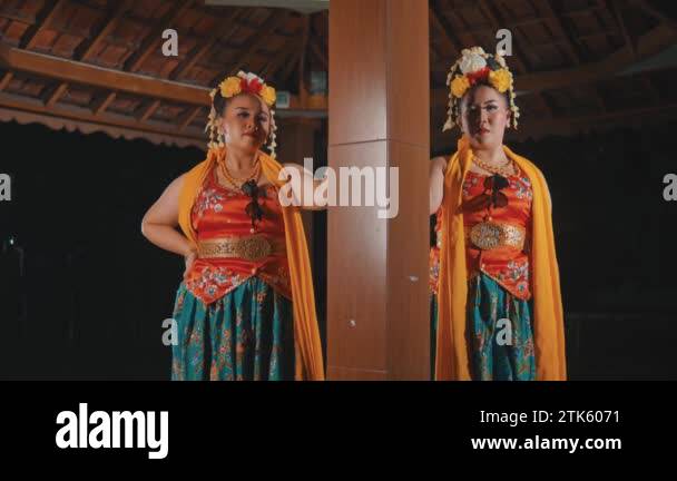 Two traditional Javanese dancers are standing between the pillars of a ...