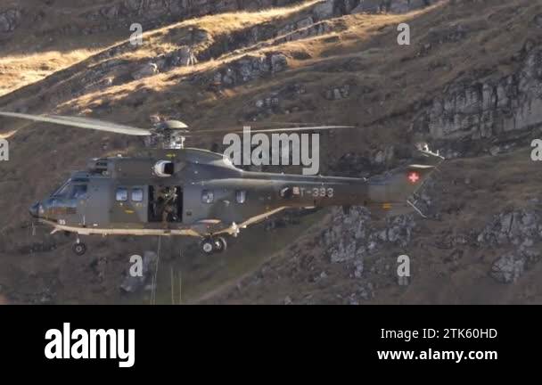Military helicopter in flight at high speed in a narrow mountain valley ...