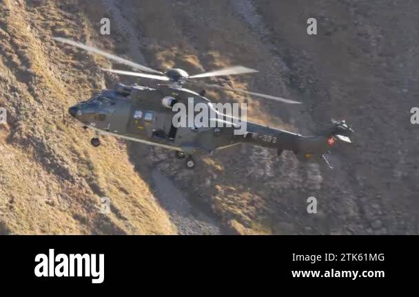 Military helicopter in flight at high speed in a narrow mountain valley ...