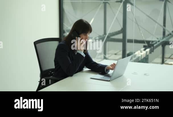 In a office setting, observe a skilled businesswoman adeptly managing a phone call while ...