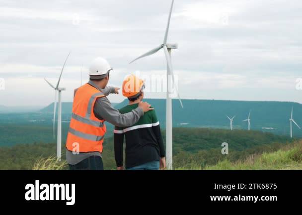 Engineer with his son on a wind farm atop a hill or mountain in the ...