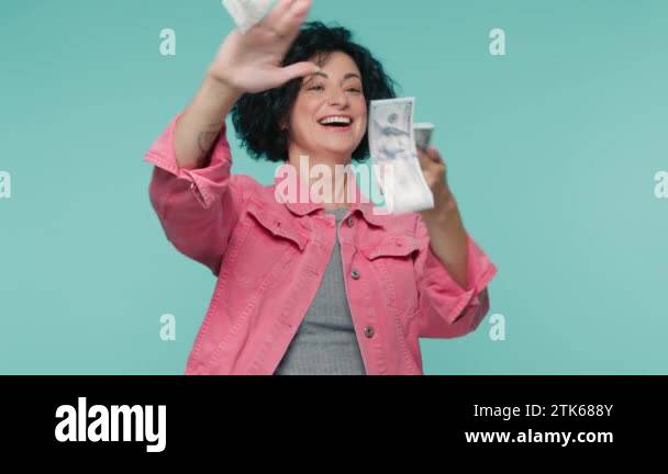 Wasteful mature woman 40s in pink jacket scattering dollars looking ...