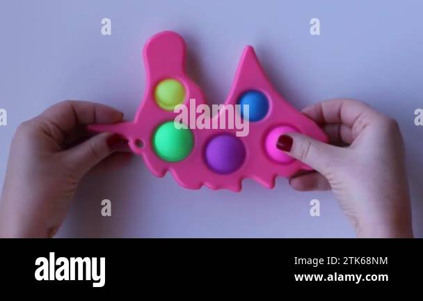 Women hands crumple and play with pink Pop It Unicorn close-up top view ...