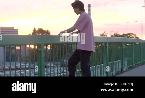 The guy climbs the railing of the bridge in the city. He swings his leg ...