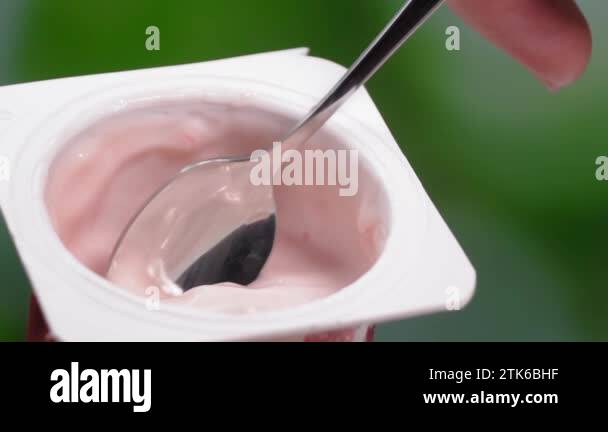 macro videography, Slow motion yogurt with spoon in cup. Hand woman ...