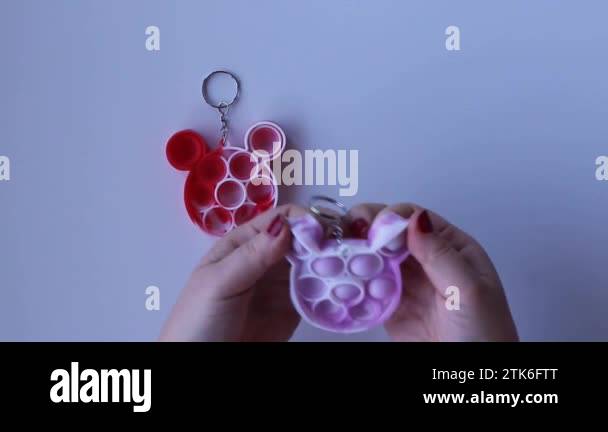 Women hands crumple and play with mouse head Pop It close-up top view ...