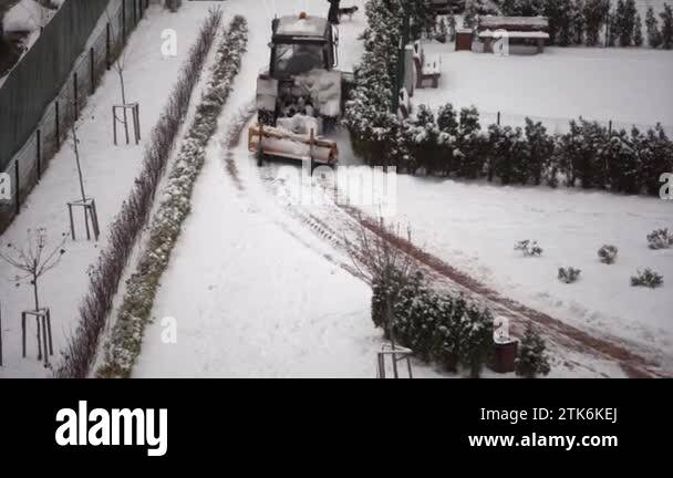Tractor sweep snow with rotating brush and snowplow from pedestrian ...