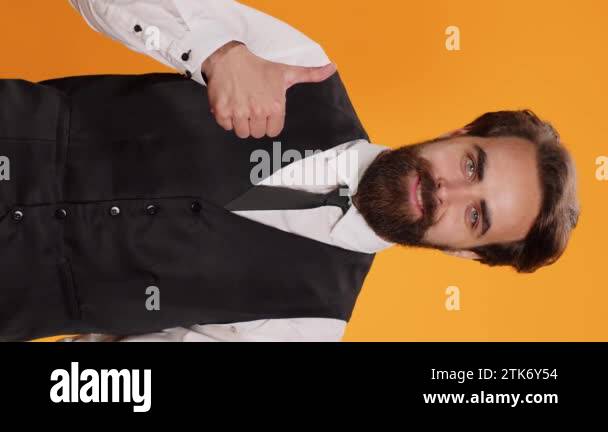 Vertical video Stylish butler shows thumbs up gesture in studio ...