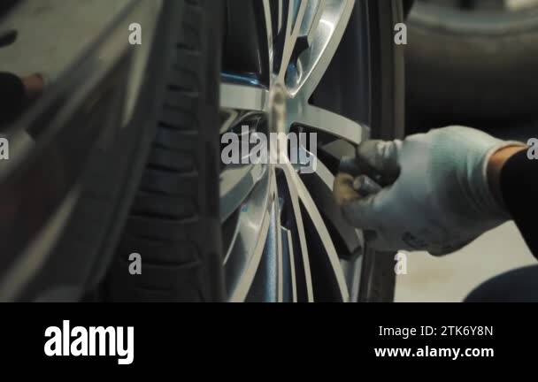 Screwing the tire bolt on the car. Tire fitting. Car wheel. Garage ...