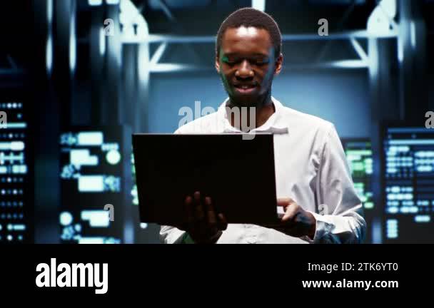 Cheerful system administrator using laptop to survey energy consumption ...