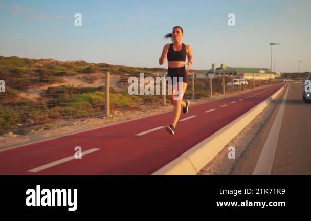 Woman run on roadside running track summer day slow motion follow shoot ...