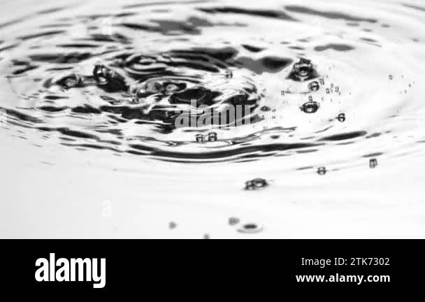 Macro shot underwater of drops falling on liquid surface and creating ...
