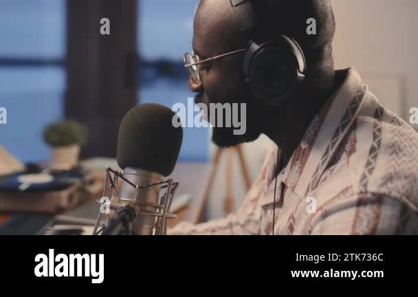 Loose close-up of black man recording audio, singing into the ...