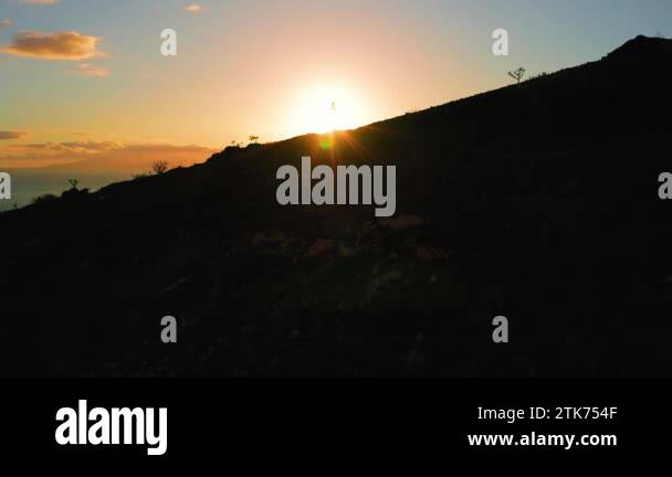 Girl silhouette illuminated by sun rays with dark natural landscape ...