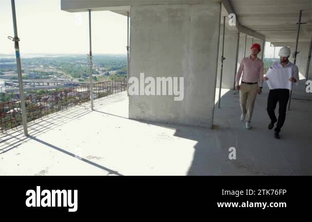Two male builders walking through the one of floors at the building ...