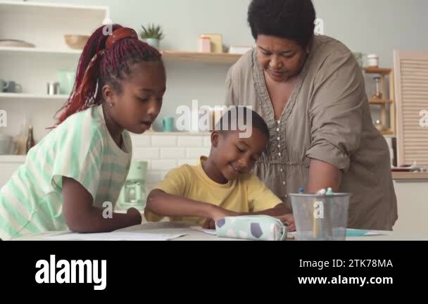 African American grandmother helping two tween grandchildren with their ...