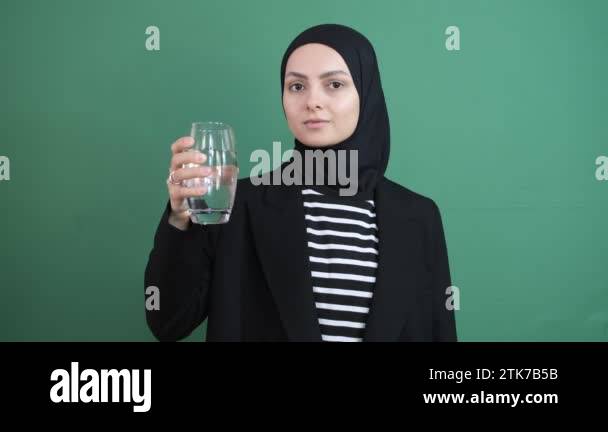 Muslim woman drinking water, girl sign water in front of green screen ...