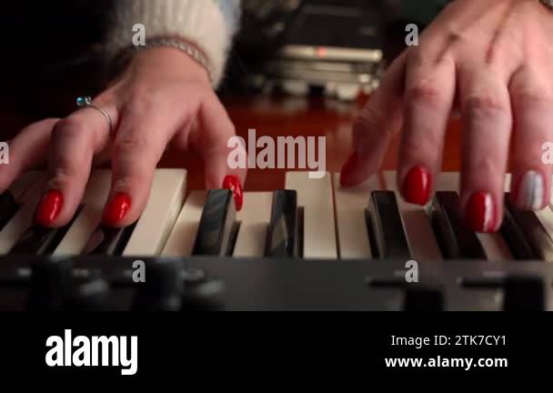 Female hands with fingers play the piano keyboard close-up front view ...