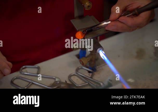 Murano glass blowing factory. Workers put iron rod in furnace to make ...