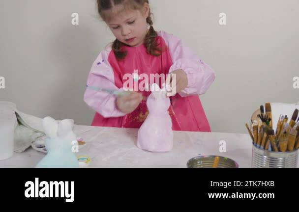 Little girl painting paper mache figurine at homeschooling art class ...