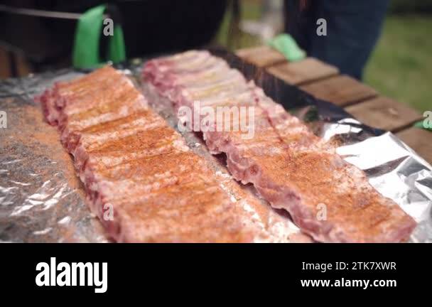 Man preparing raw pork ribs for roasting on barbecue smoker grid ...