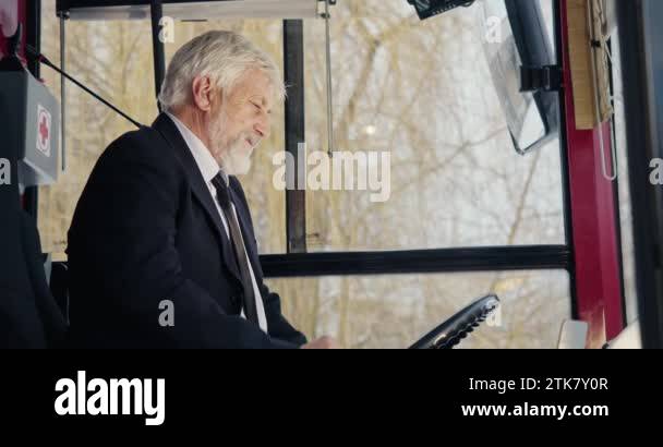 Side view of bus driver putting hands on helm. Old man with grey hair ...