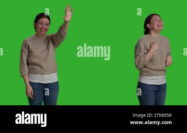 Close up of female model greeting someone and waving, smiling in studio ...