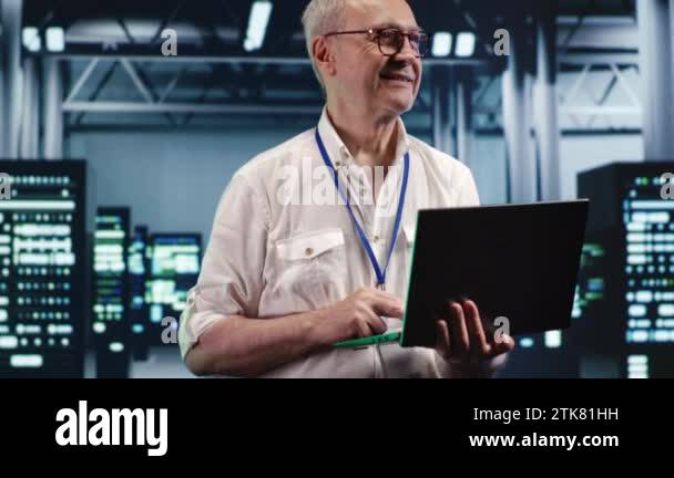 Seasoned computer scientist expertly managing data while navigating in industrial server room ...