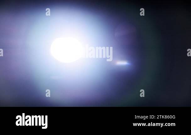 The light of a bright flashlight directed at the camera moves from side ...