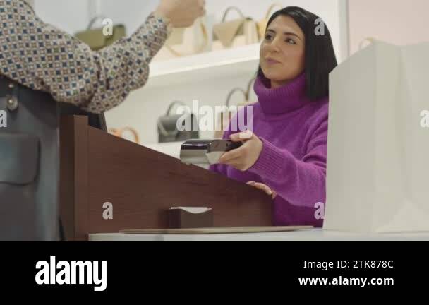 Contemporary woman taking credit card out of her wallet while paying ...