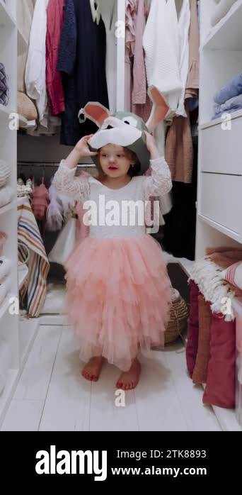 cute baby girl having fun in a walk-in wardrobe closet with apparels on ...