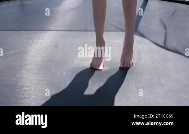 Close up view on childrens feet bouncing on a trampoline. Slow motion ...