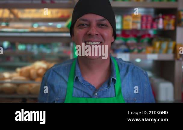 Portrait of a Brazilian employee of deli shop smiling, standing behind ...