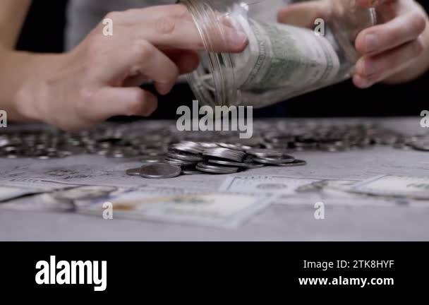 Woman Pours Change and a 100 Dollar Bill from a Glass Jar onto the ...