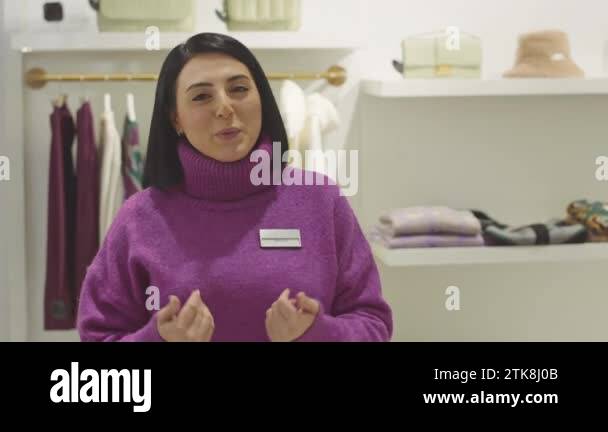 Young attractive Middle Eastern shop assistant talking at camera while ...